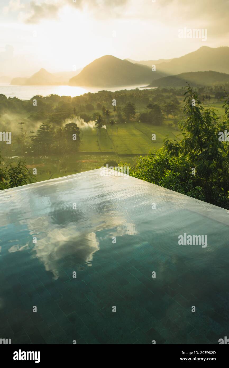 Infinity pool with amazing mountain and ocean view at sunset. Sun rays ...