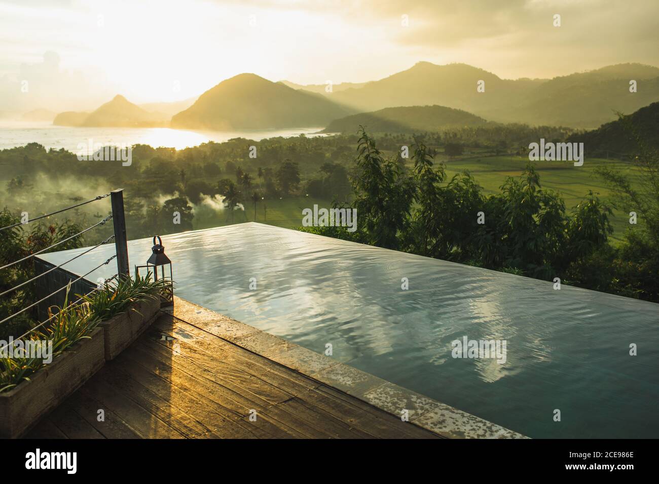 Infinity pool with amazing mountain and ocean view at sunset. Sun rays ...