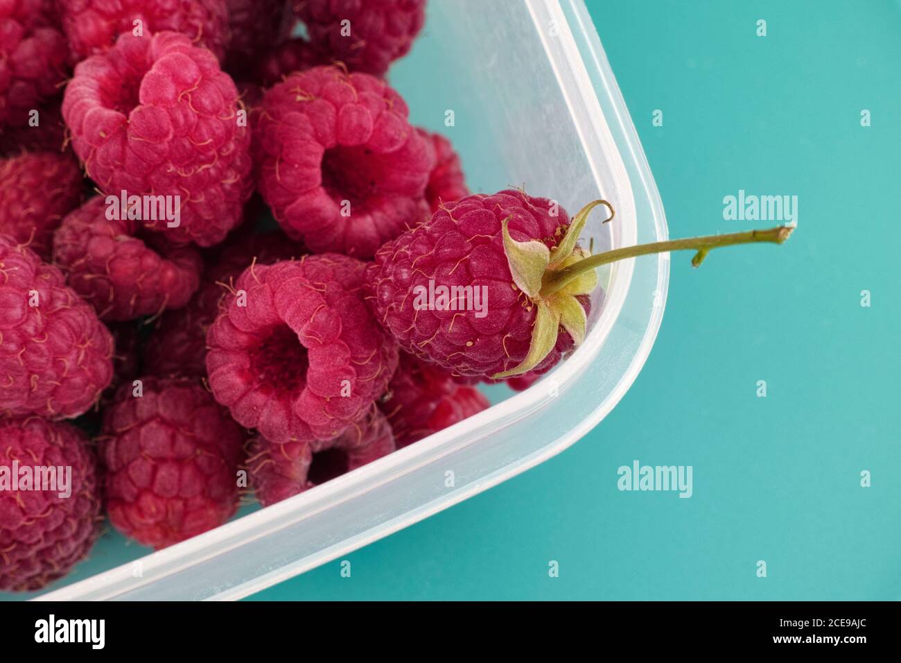 Organic raspberries in a plastic container. Close up Stock Photo - Alamy