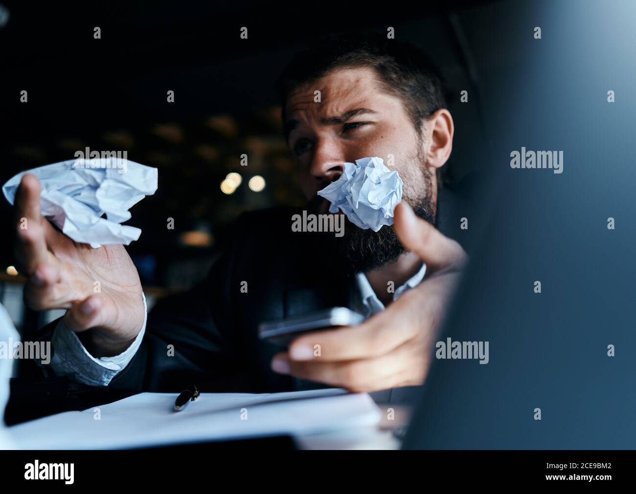 business man sitting at table in front of laptop crumpled paper ...