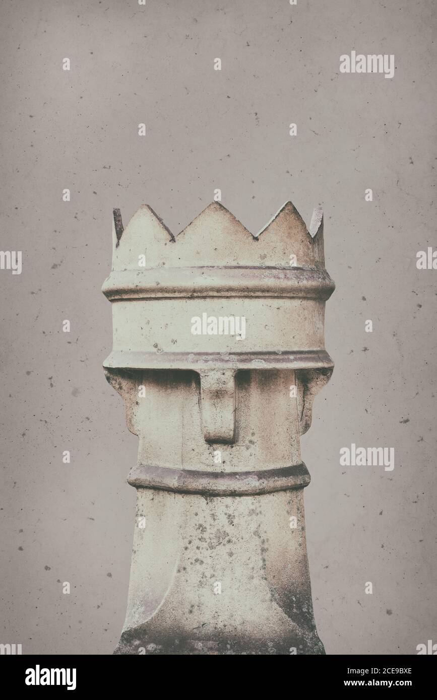 Ancient stone weathered chess tower in front of a grey concrete wall ...