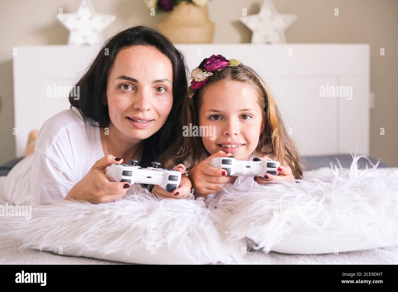 Little girl and mom are playing a computer game with mom. Jostics in ...