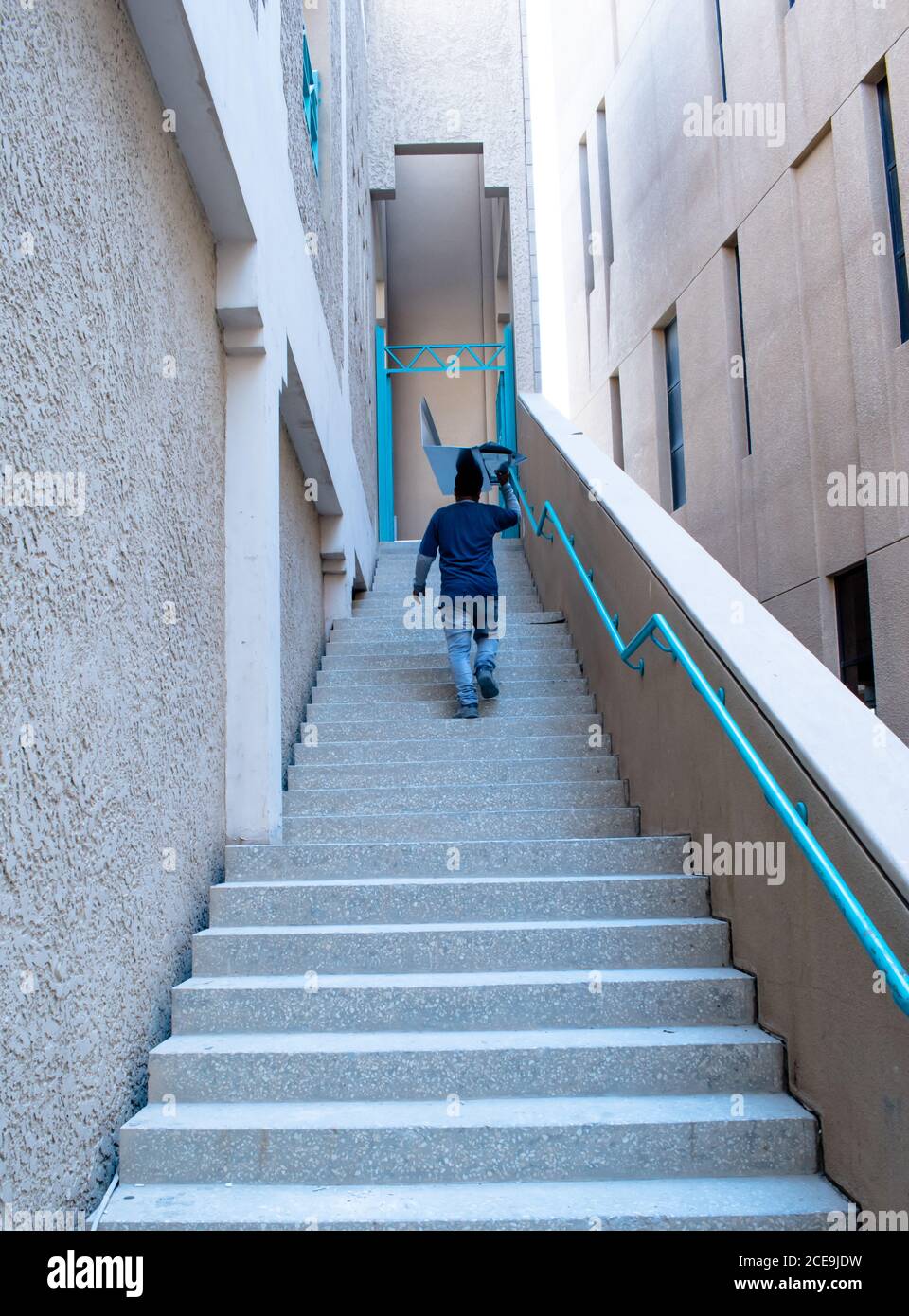Man carrying metal object above his shoulder walking in the stairway ...