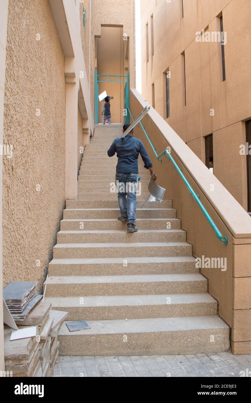 Man carrying metal object above his shoulder walking in the stairway ...