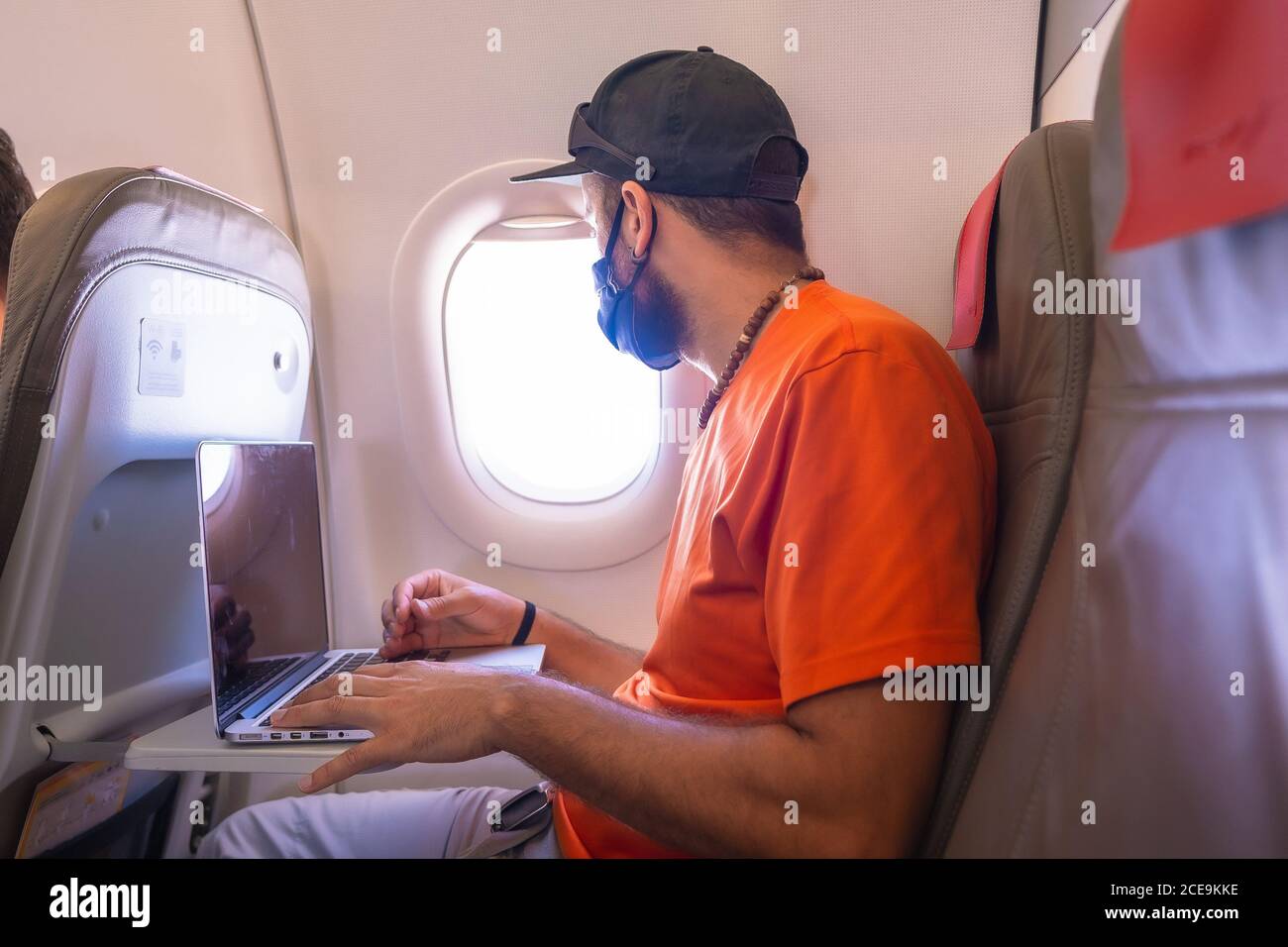New normal - a male wearing a mask on the airplane Stock Photo - Alamy