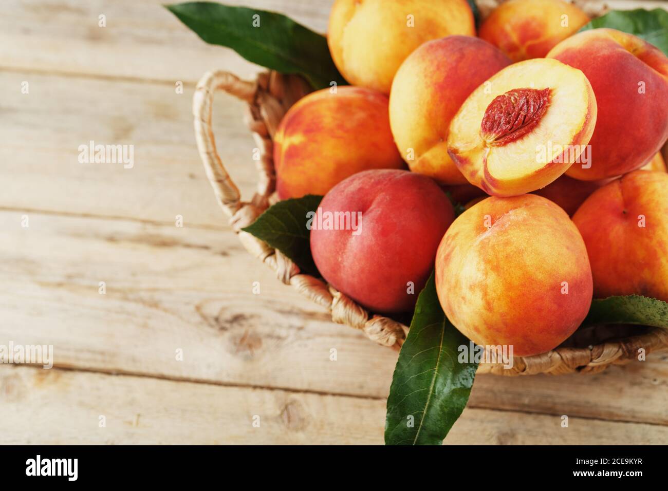 Peaches in a basket on a wooden background with a slice of sliced juicy ...