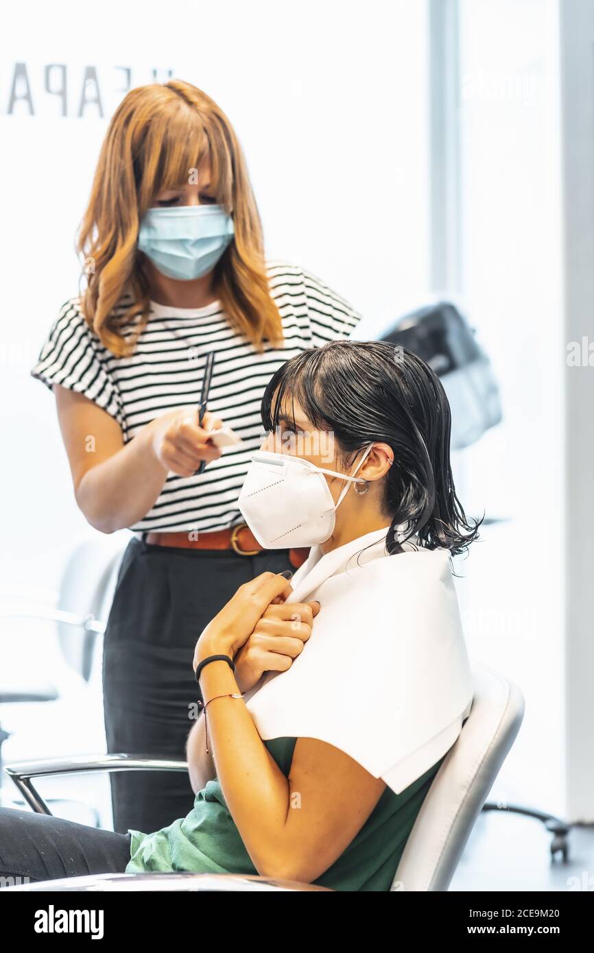 Vertical shot of a female in a protective face mask getting a haircut ...