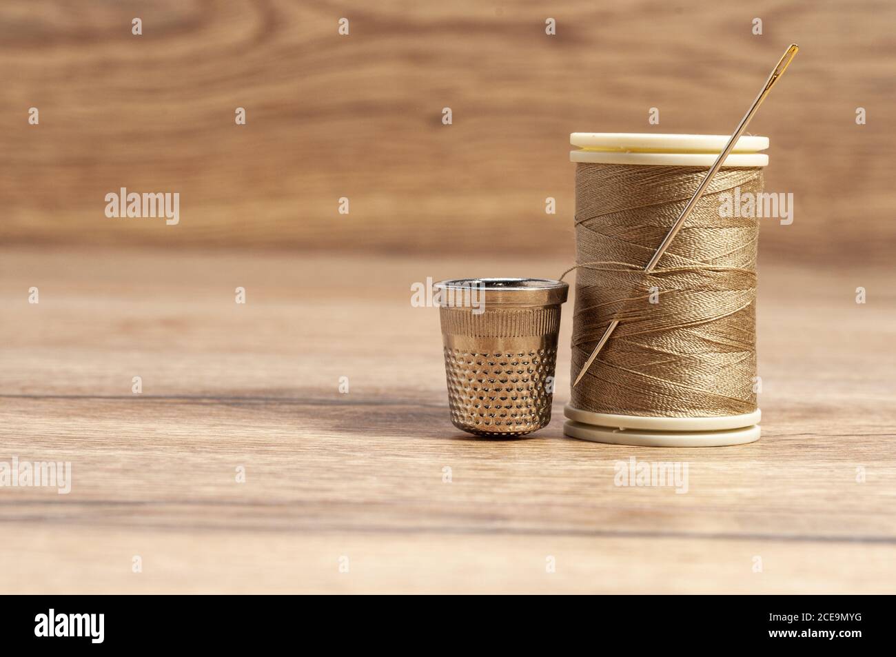 Roll of brown thread with a needle and a thimble Stock Photo - Alamy