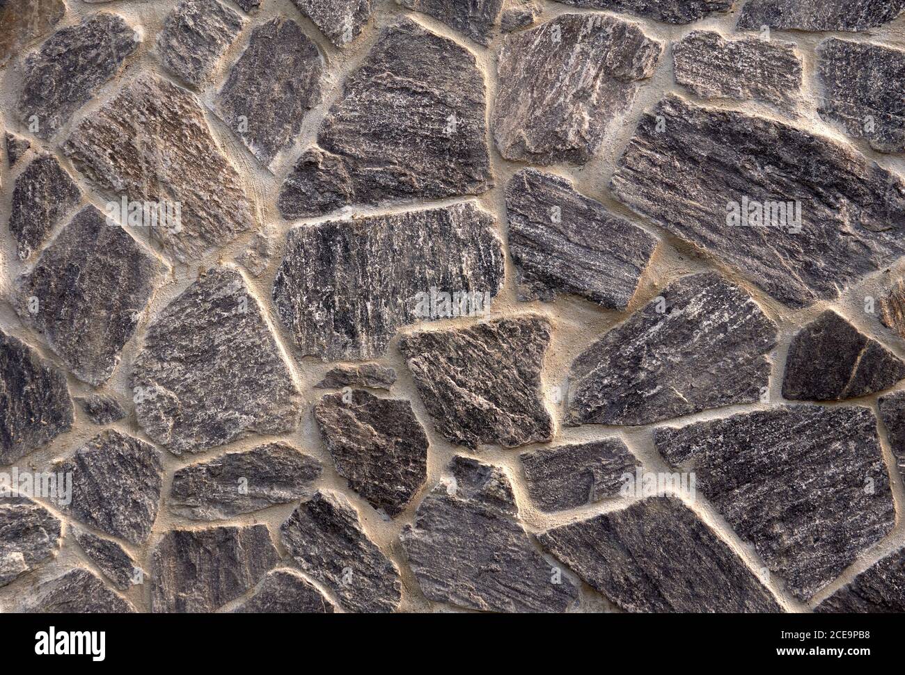 Natural grey granite stones inset in the stucco wall of a house forming ...