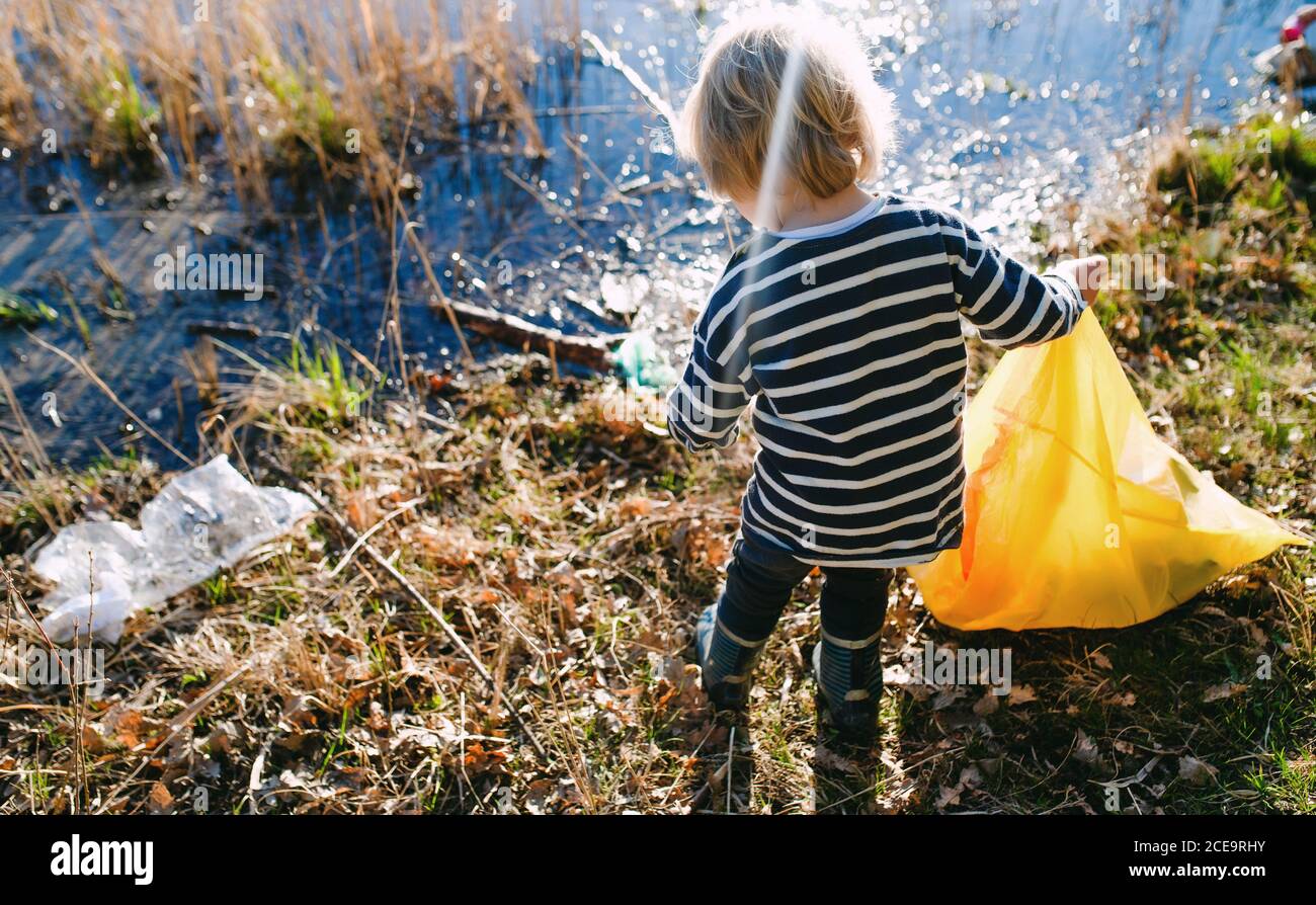 Unrecognizable small child collecting rubbish outdoors in nature ...