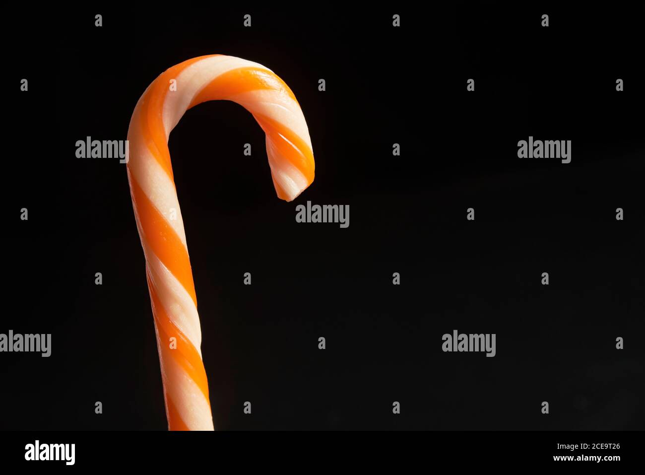 Halloween orange and white striped candy cane on black background with ...