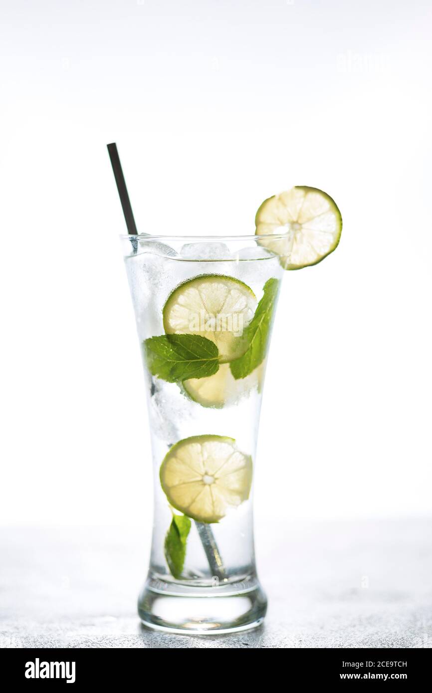 Cold refreshing beverage with sliced lime ripes and ice reverse light image in studio with white ...