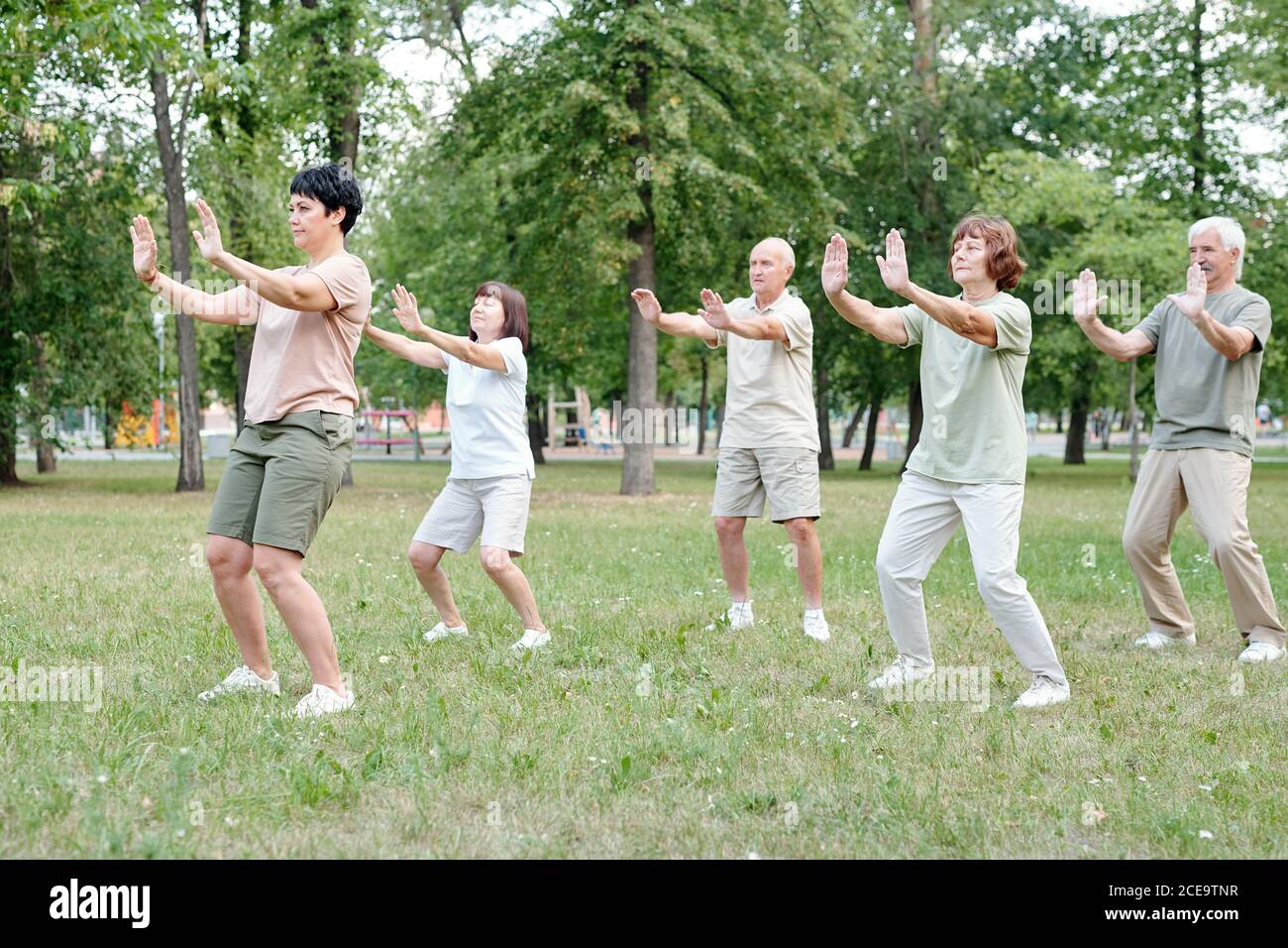 Focused coach raising hands forward while showing relaxing exercise to ...