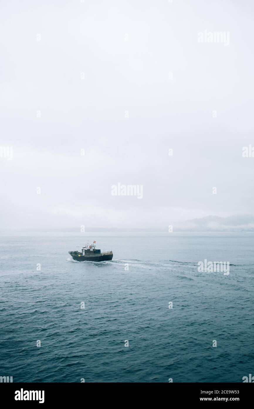 Vertical outdoors shot of a boat floating in the blue sea. Vertical ...