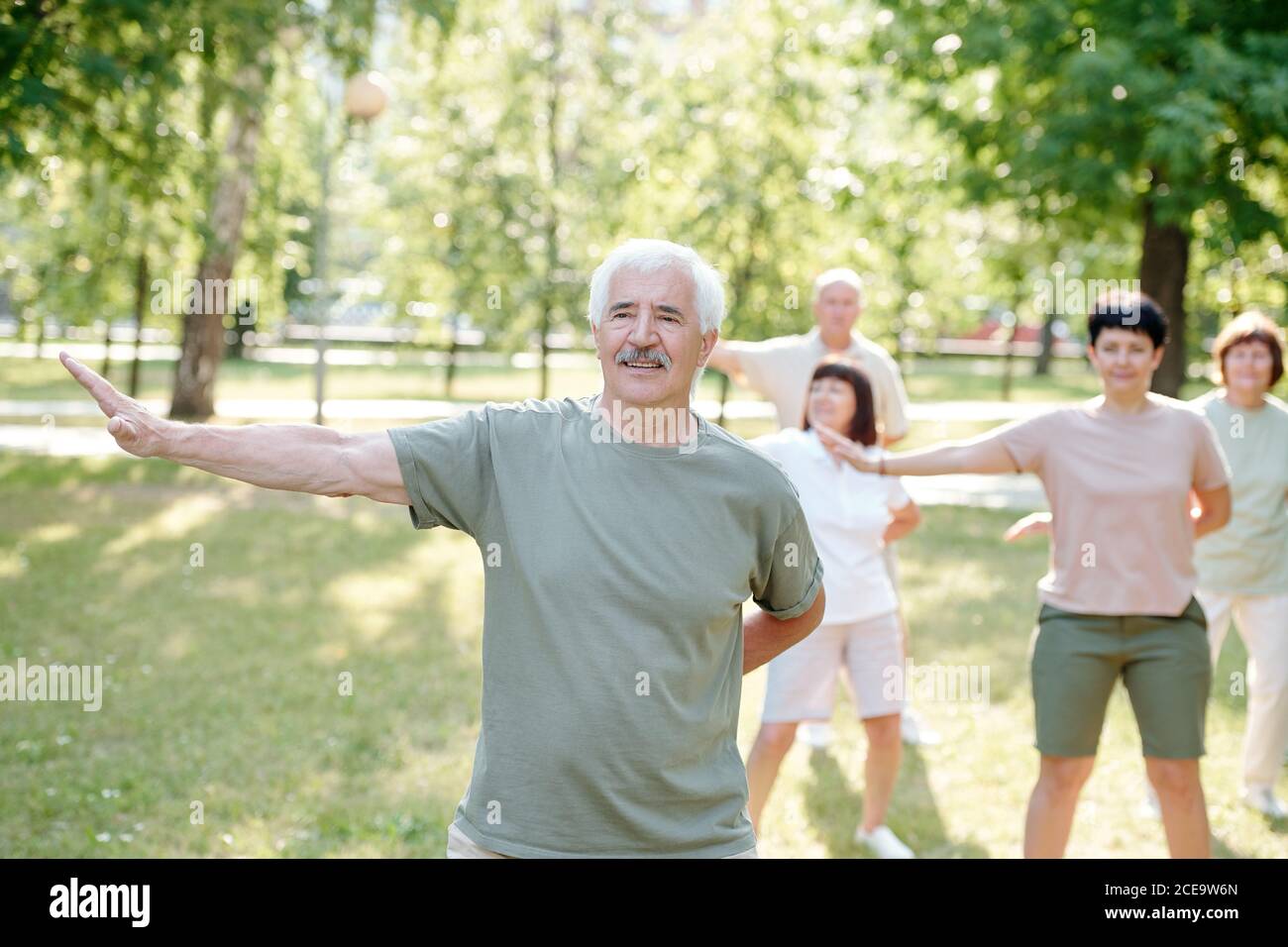 Handsome senior man with mustache practicing qigong exercise to be ...