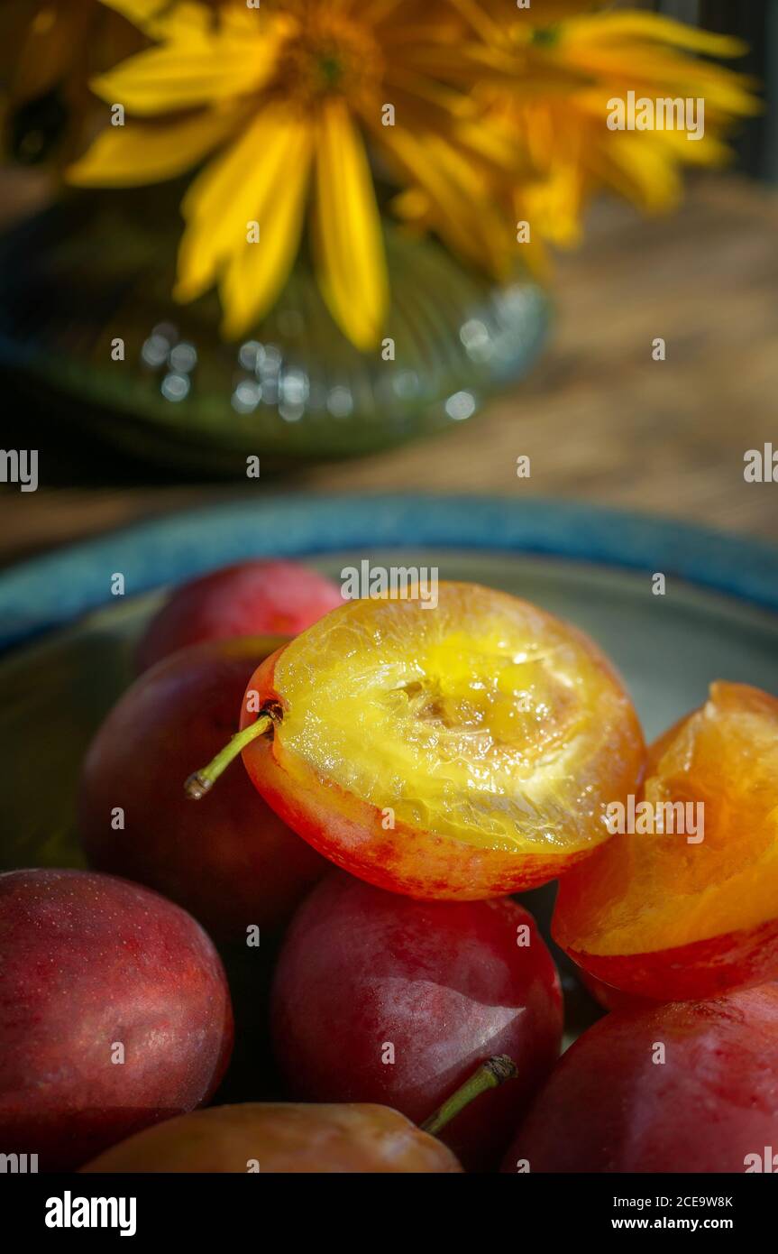 Ripe large juicy red plum lies in a beautiful plate on a wooden rustic ...