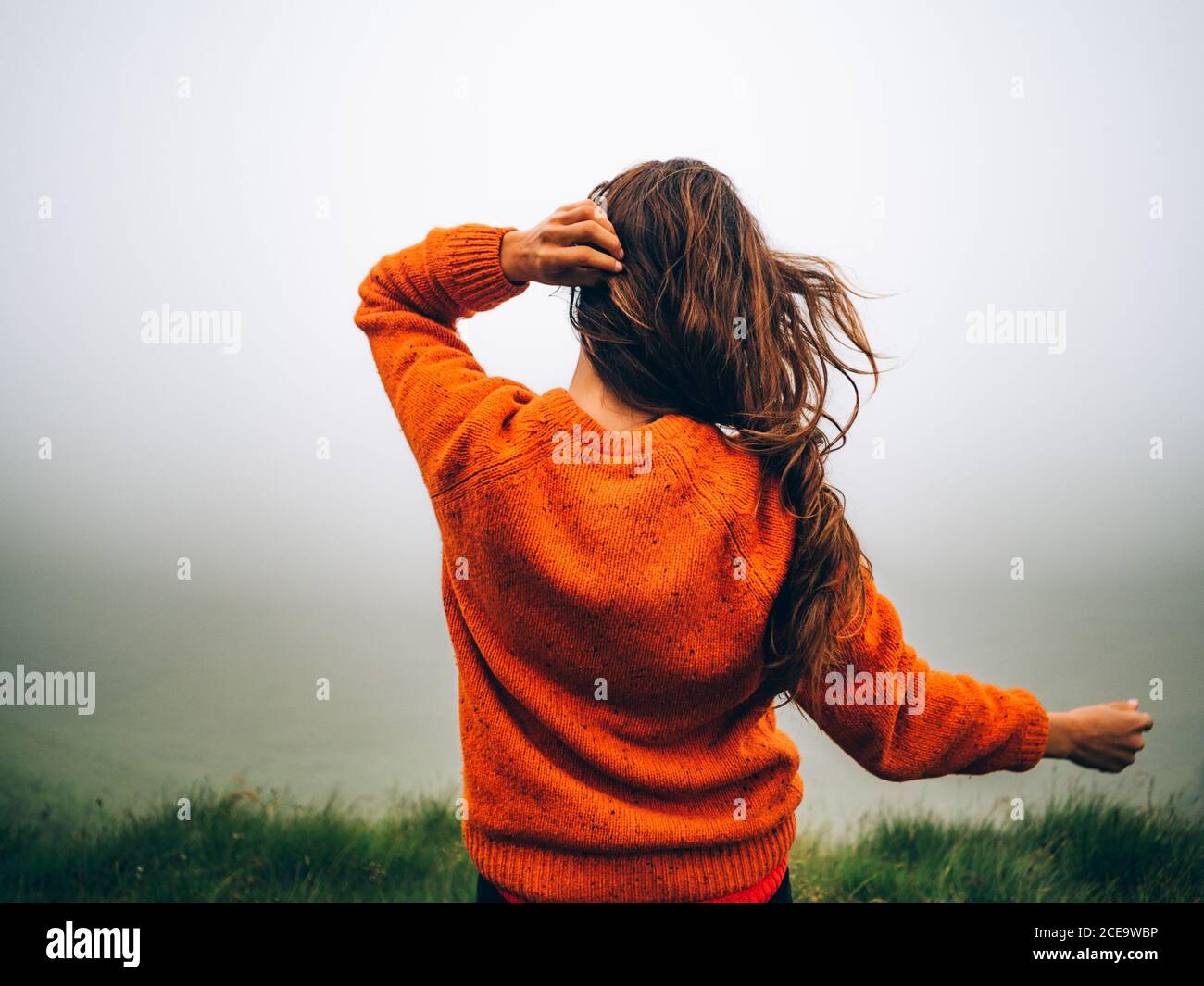 Back view woman windy hair green meadow fog highlands hi-res stock ...