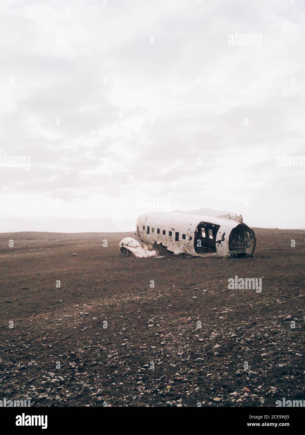 A broken airplane body lying on the empty ground. Vertical outdoors ...