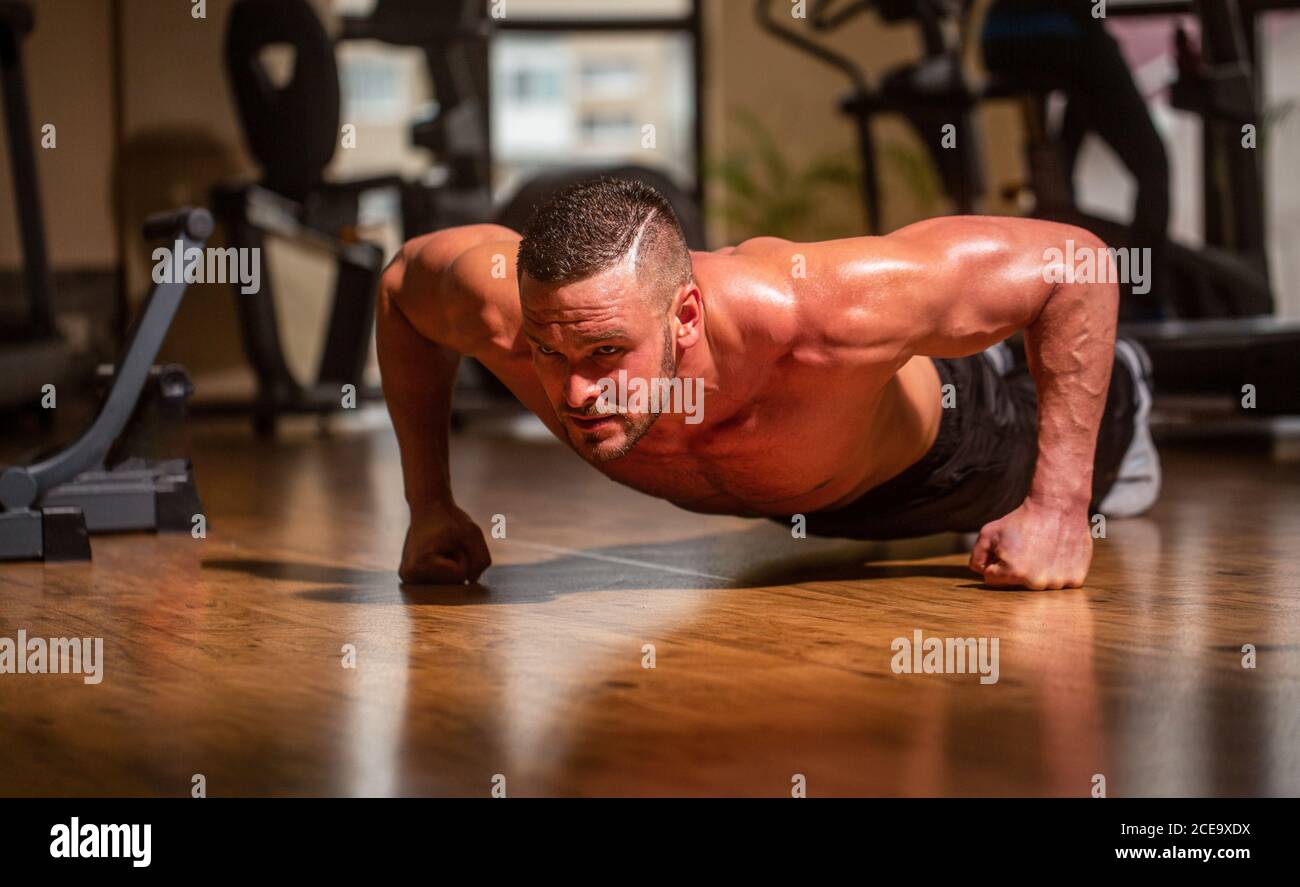 Muscular man doing push-ups on one hand against gym background. Sport ...