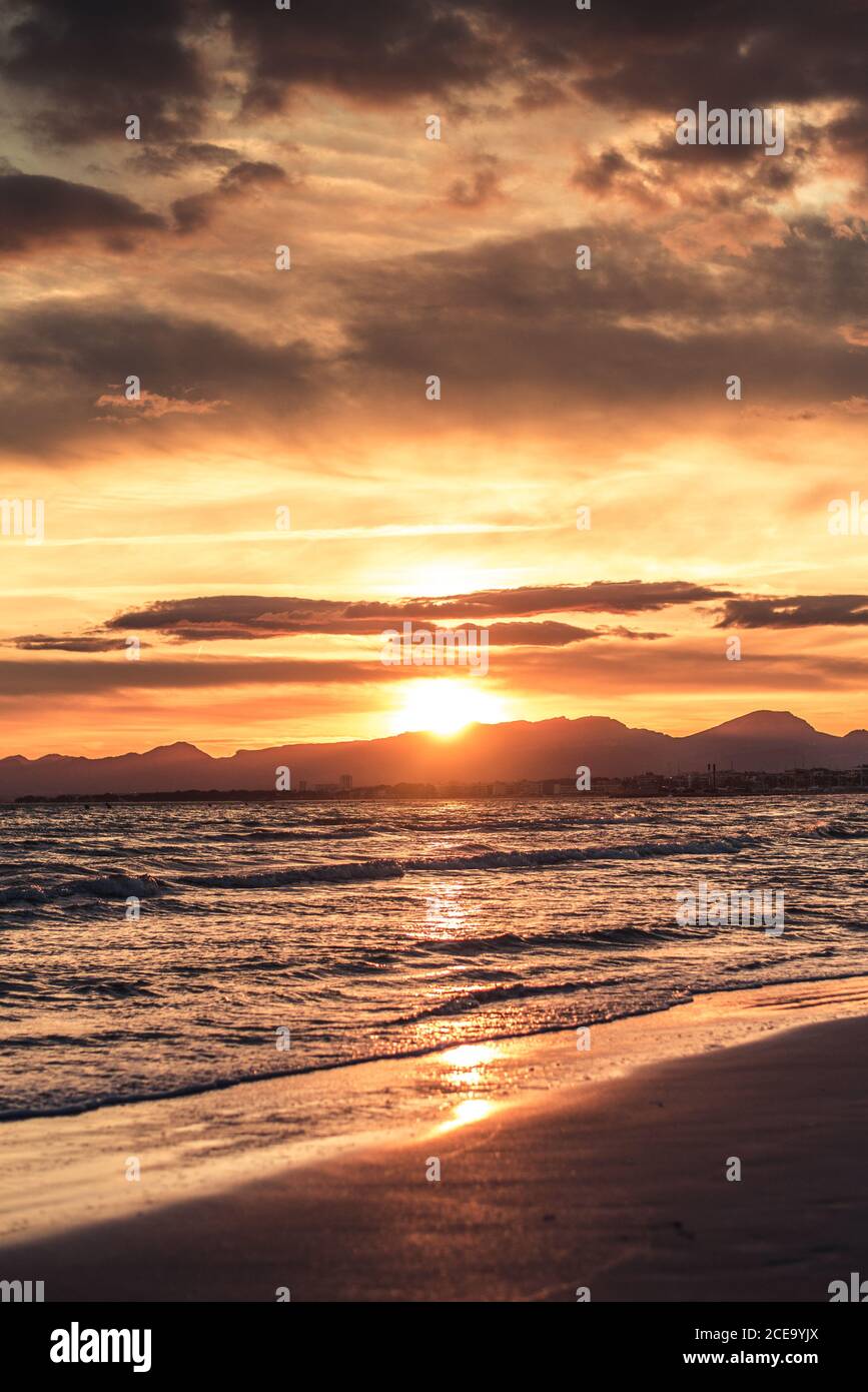 Bright golden sun glowing and reflecting in ocean waves washing calmly ...