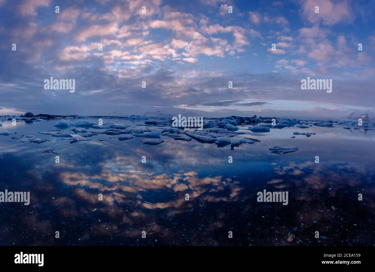 View to calm lake and pieces of ice floating in cloudy day Stock Photo ...