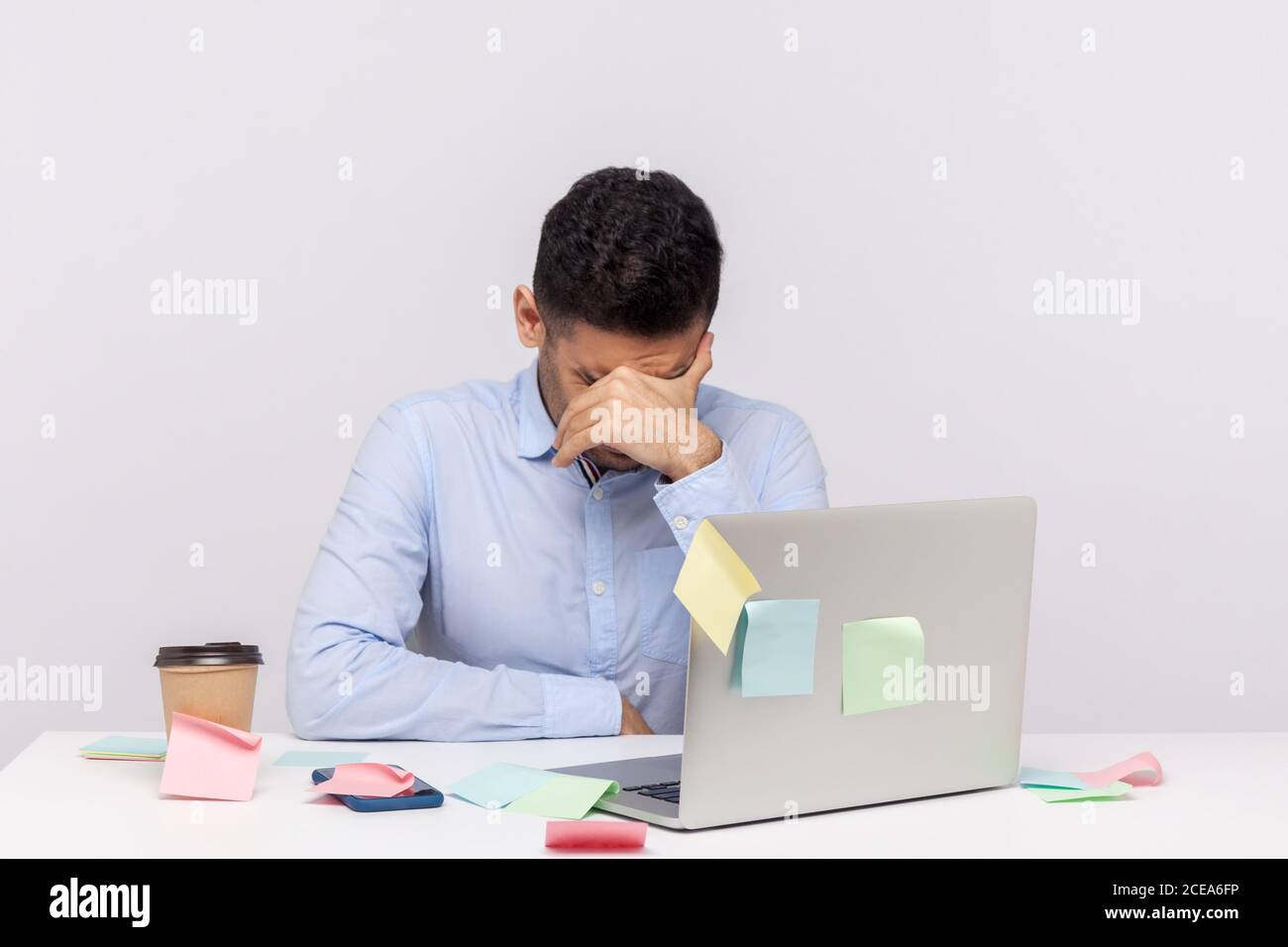 Tired unhappy man employee sitting in office workplace with sticky ...