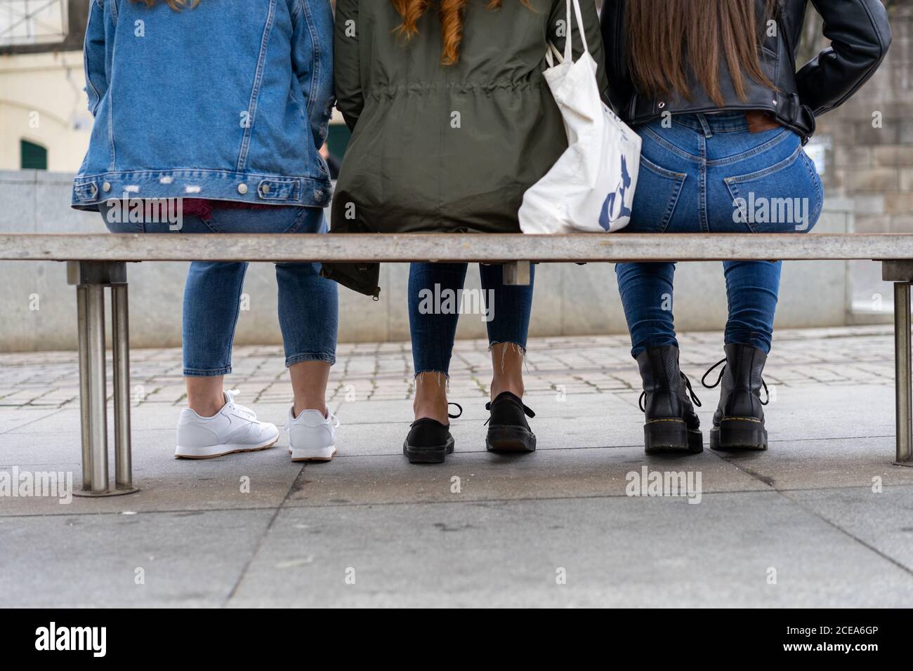 Young ladies in casual wear sitting on bench Stock Photo - Alamy