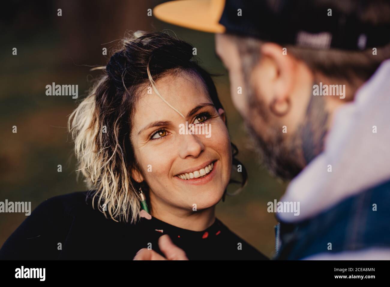 Bearded man embracing from back cheerful young lady near wood in forest ...