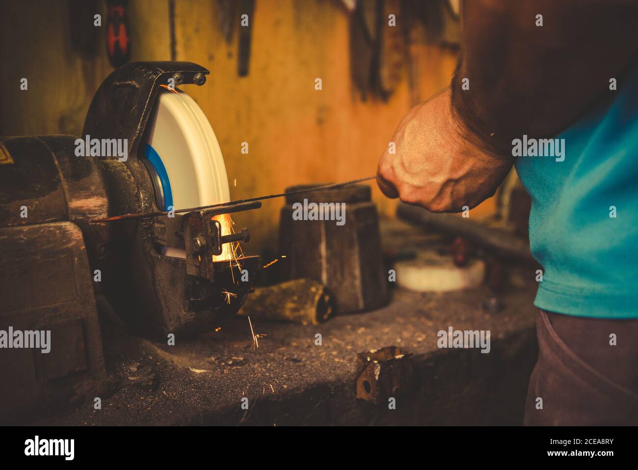 Crop smith using grindstone to sharpen metal blade in professional ...