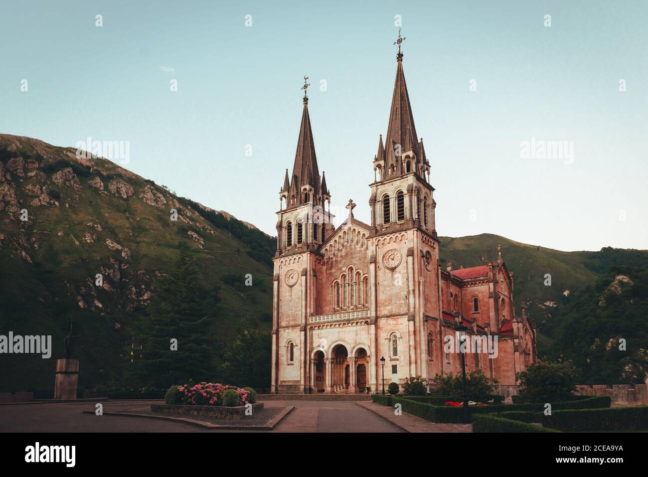 Wonderful ancient monastery with green plants on court near mountain ...