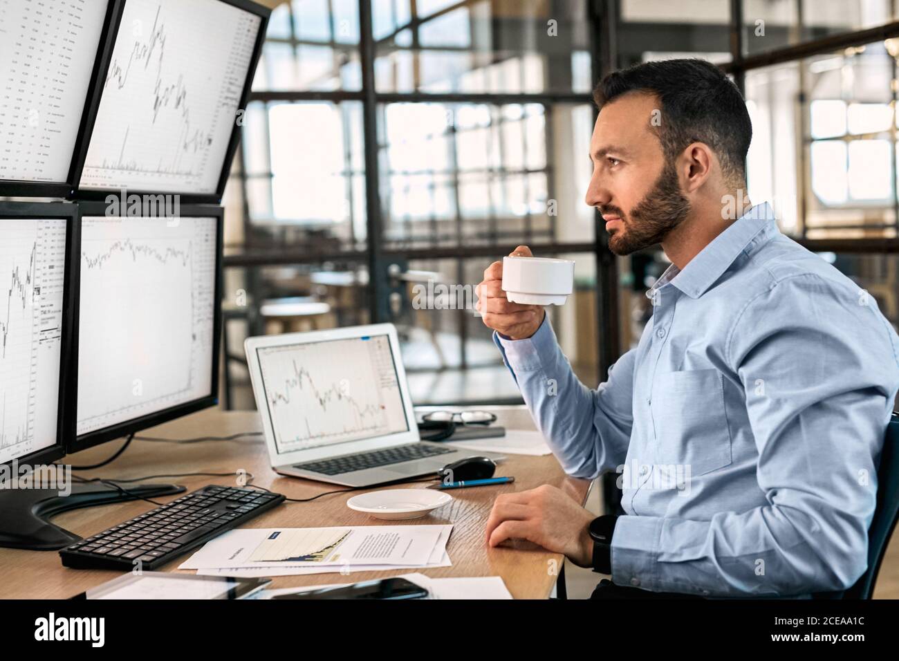 Stock Traiding. Trader sitting at office in front of monitors looking ...