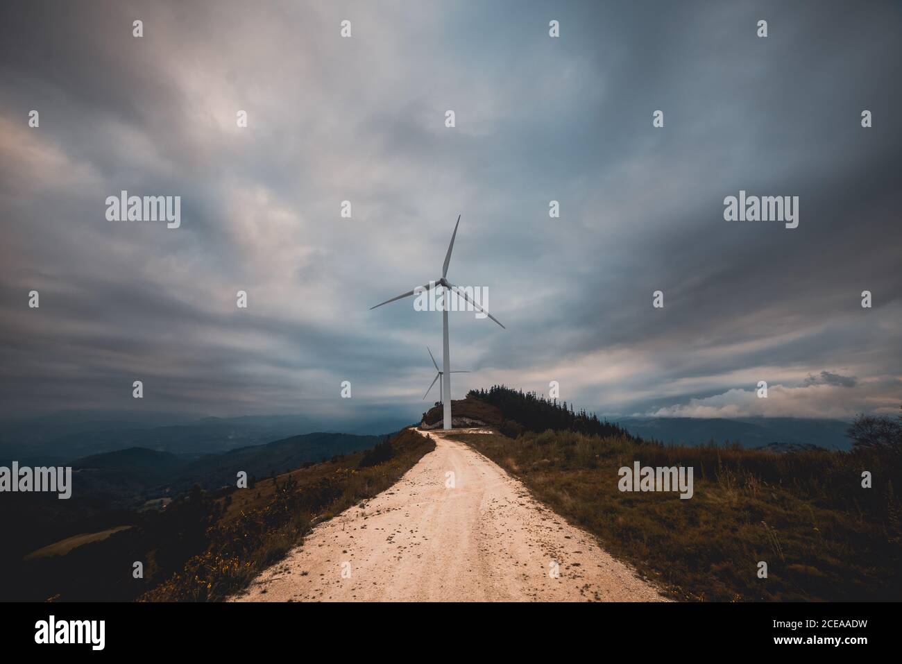 Row of modern windmills standing on side of narrow countryside road on ...