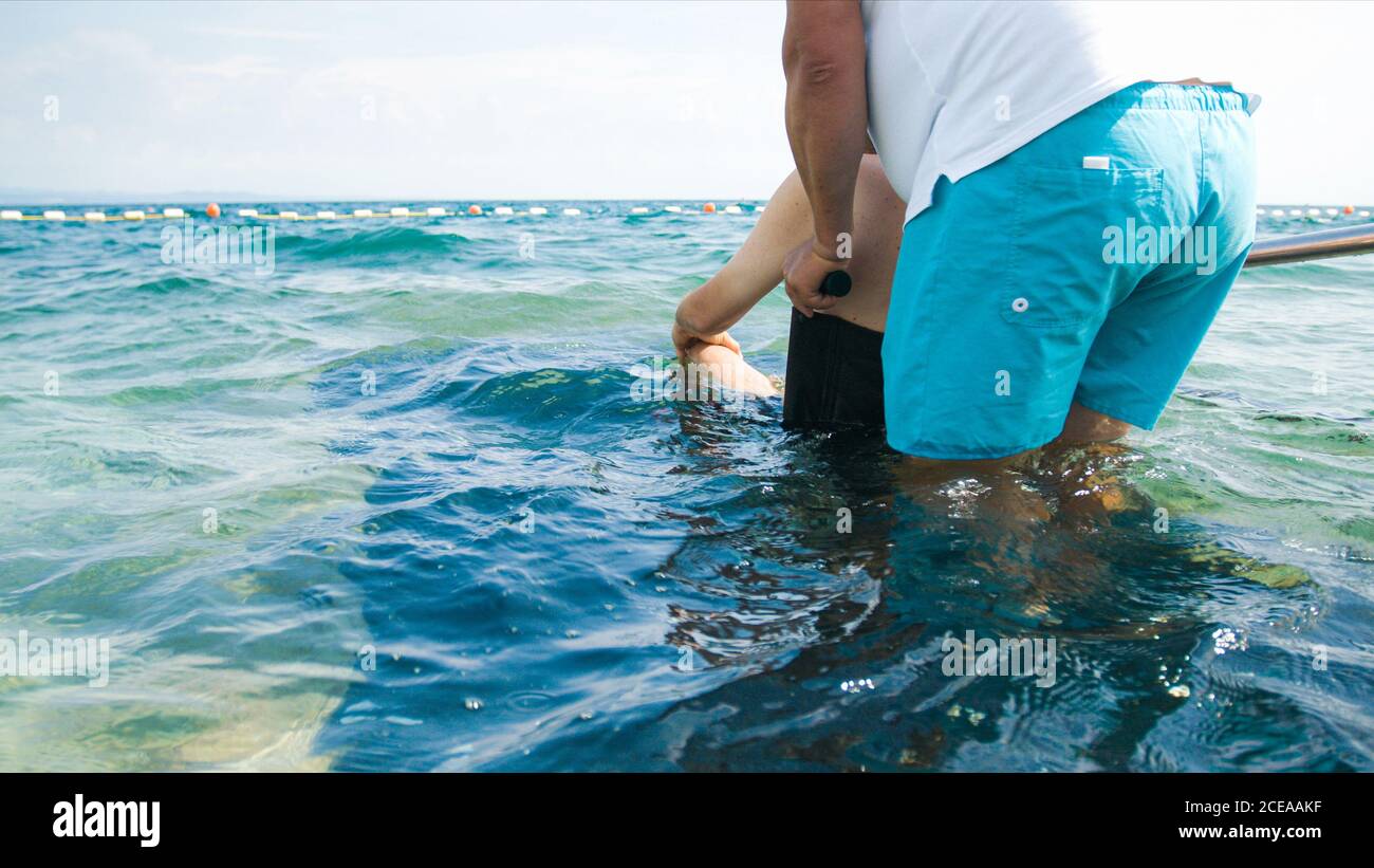 Disabled man at beach swimming on a wheelchair with assistance help on ...