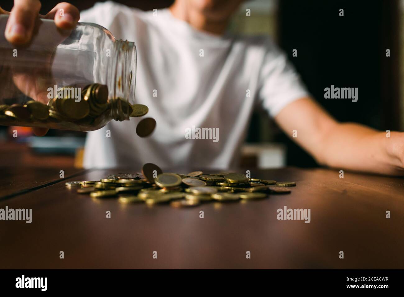 Crop guy spilling coins from jar Stock Photo - Alamy