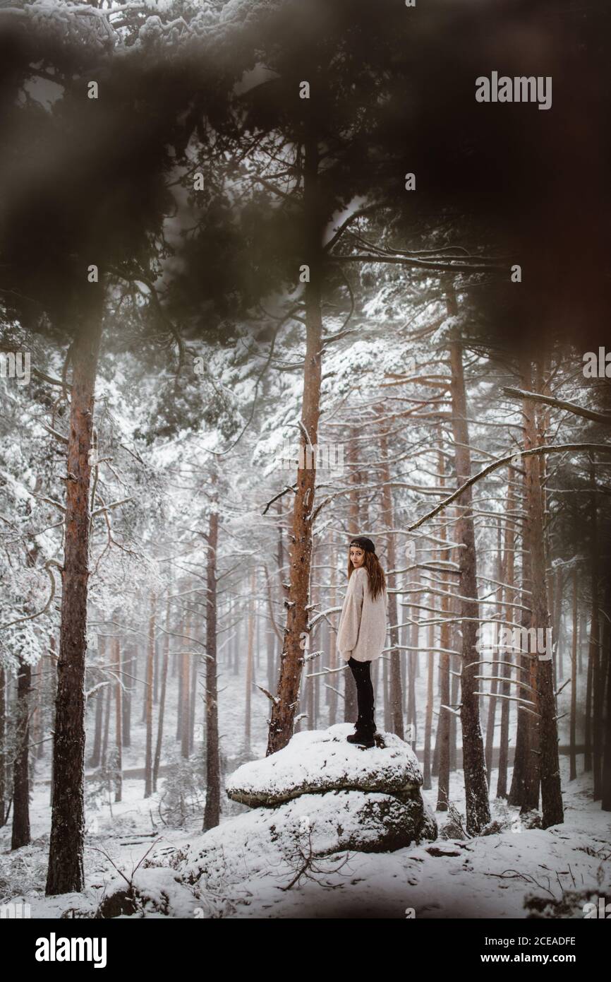 Young pretty Woman standing in winter forest and looking back at camera ...