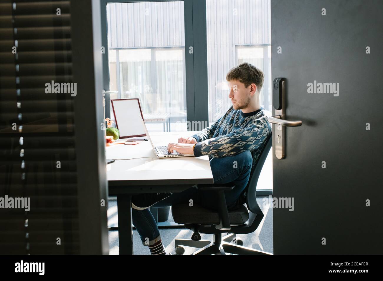 Side view of male in casual clothes sitting comfortably on office chair ...