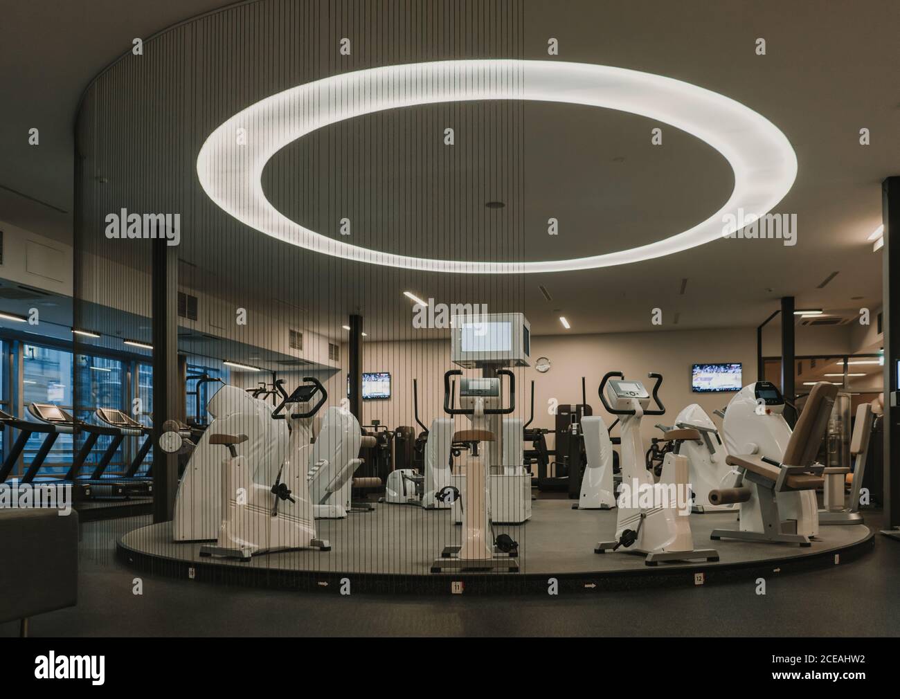 Various modern exercise machines standing in circle under huge lamp ...