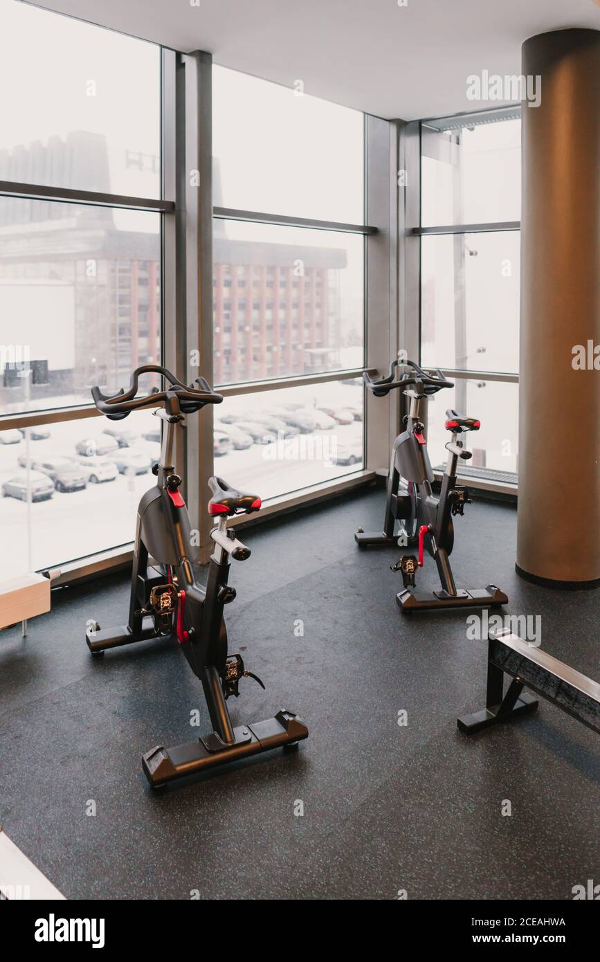 Two modern exercise bikes standing near huge window inside stylish gym ...
