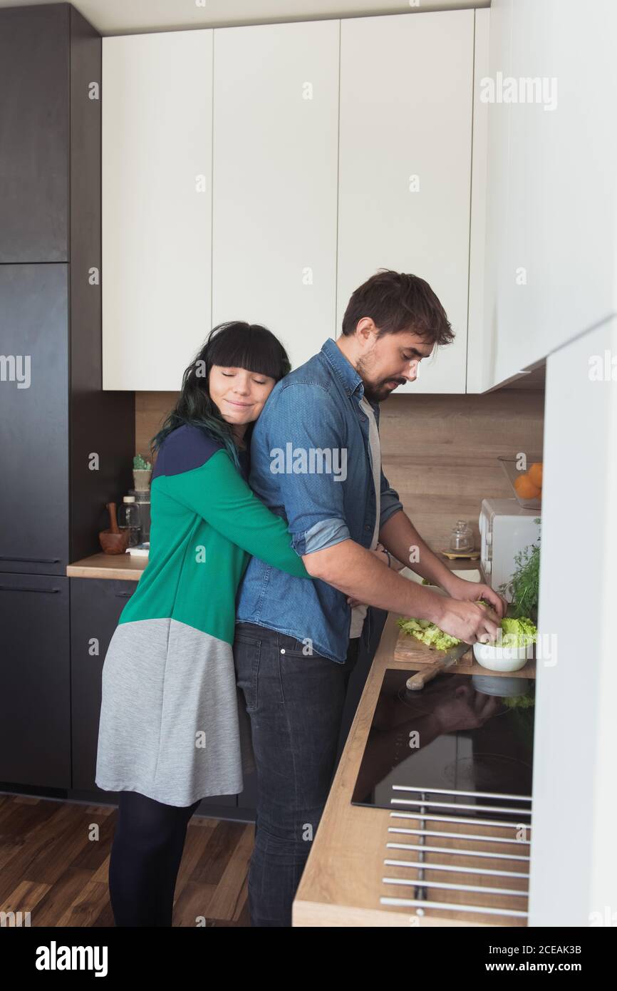 Side view of beautiful young female keeping eyes closed and hugging ...