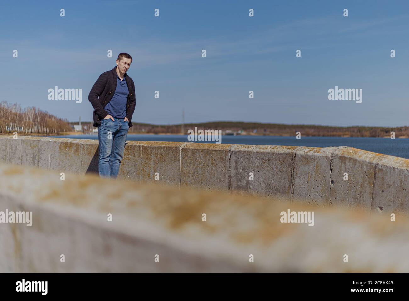 A young adult man in a black knitted jacket and jeans stands on the ...