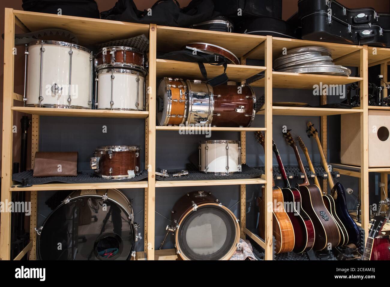 Nice wooden shelf with various drums and guitars standing in rehearse ...
