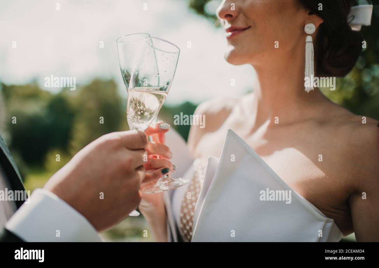 Crop bride and groom clinking glasses of fine champagne while standing ...