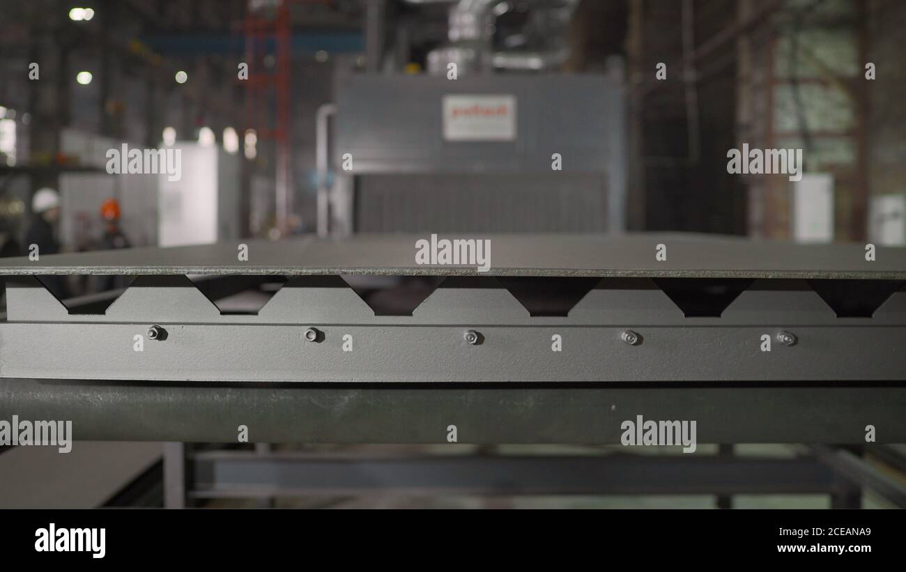 Continuous sheet of metallic material being fed through machine. Metal ...