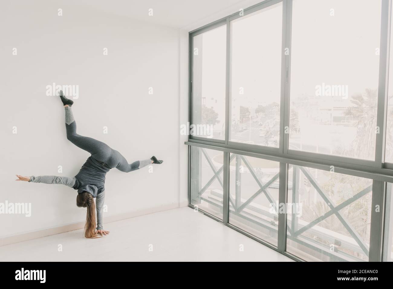Back view of young sportive Woman doing handstand and leg split in ...