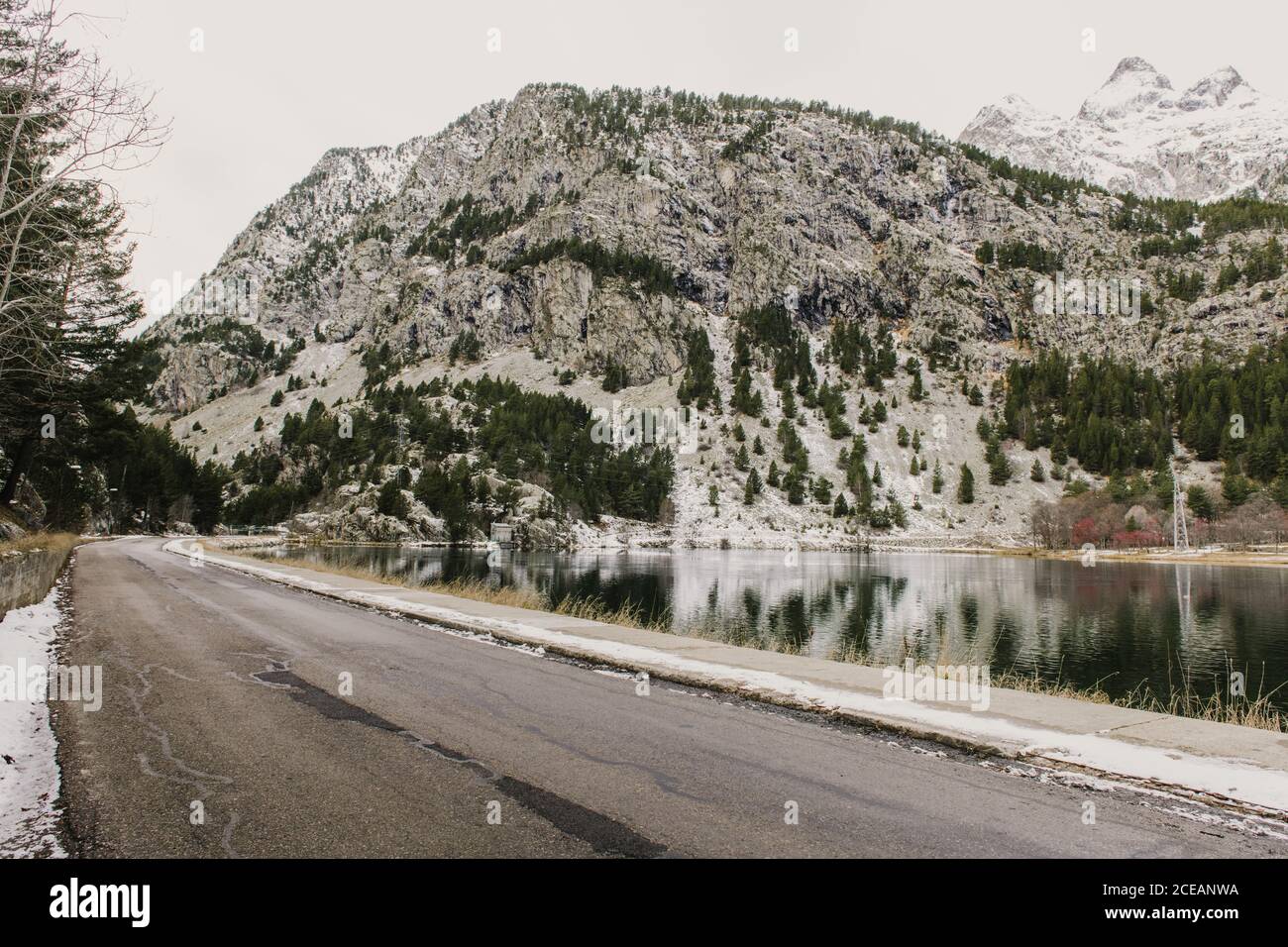 Snowy route running between mountains and a lake in Pyrenees Stock ...