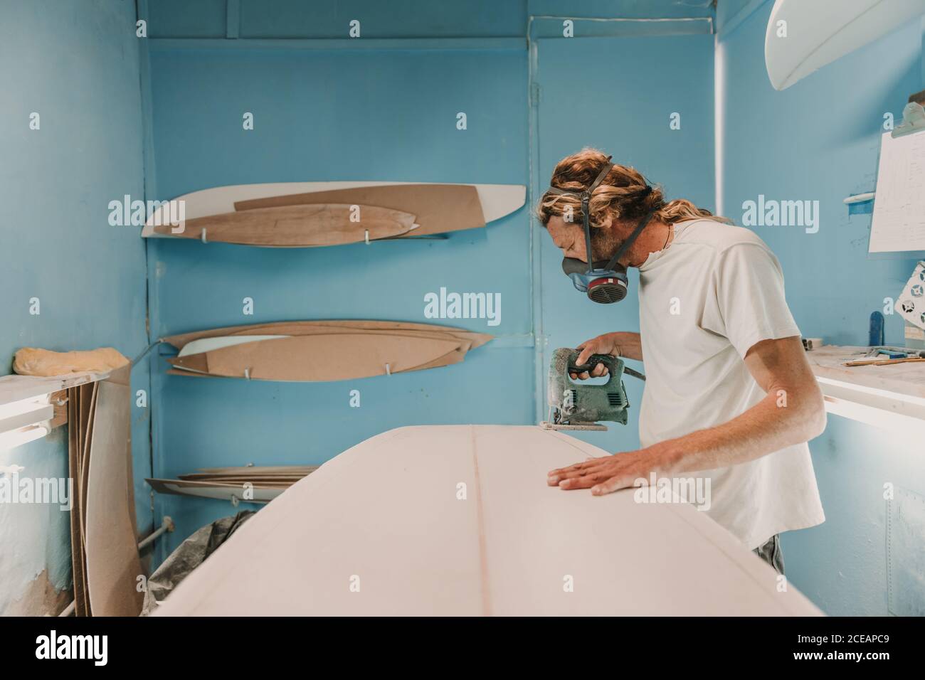 man with tool sawing surf board in workshop Stock Photo - Alamy