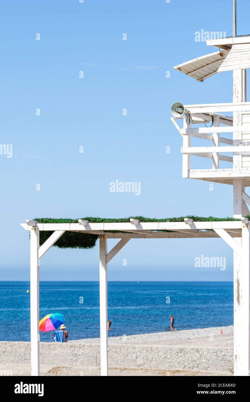 White wooden watchtower on the beach with a colorful umbrella on the ...