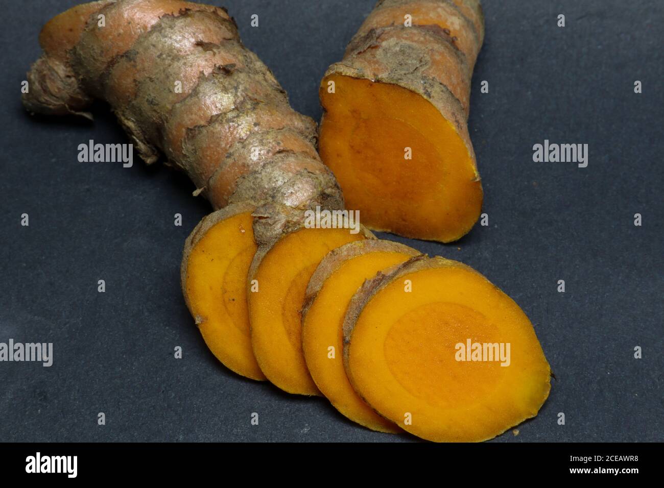 Light yellow turmeric slices on a black background Stock Photo - Alamy