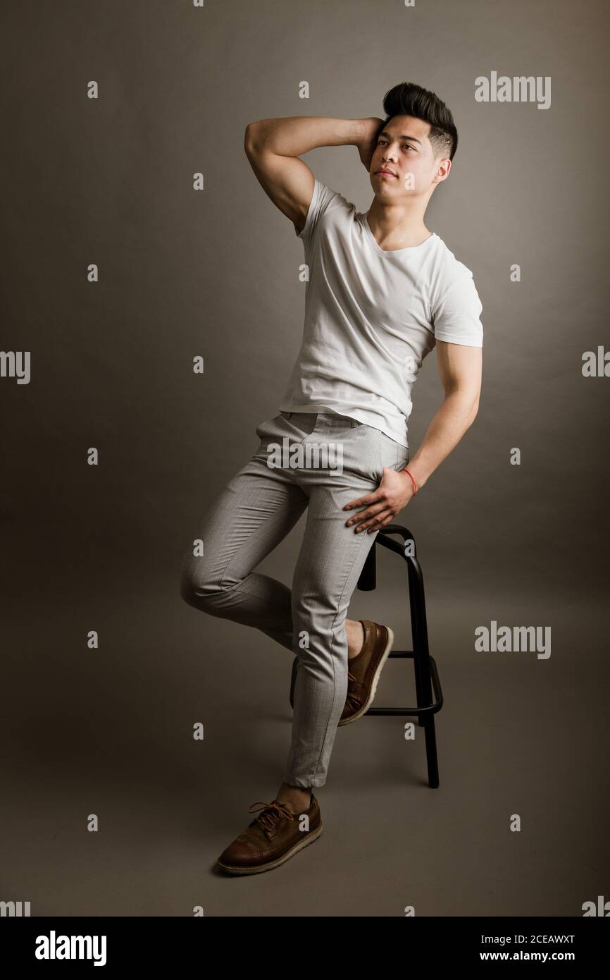 Young man sitting on chair in studio Stock Photo - Alamy
