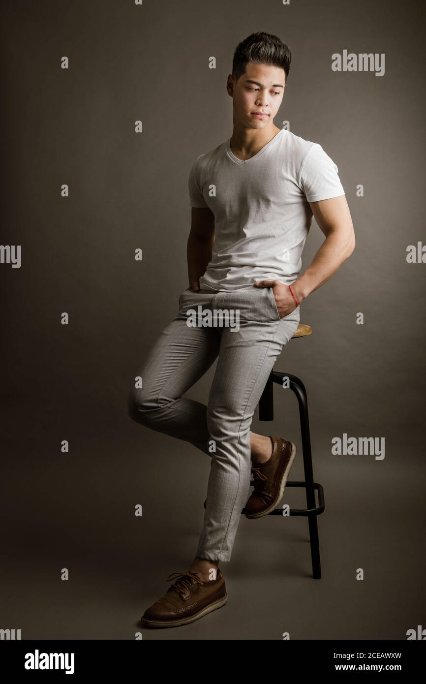 Young man sitting on chair in studio Stock Photo - Alamy